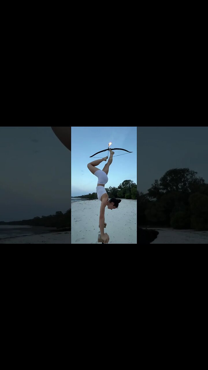 She shooting an arrow with her feet while doing a handstand on beams