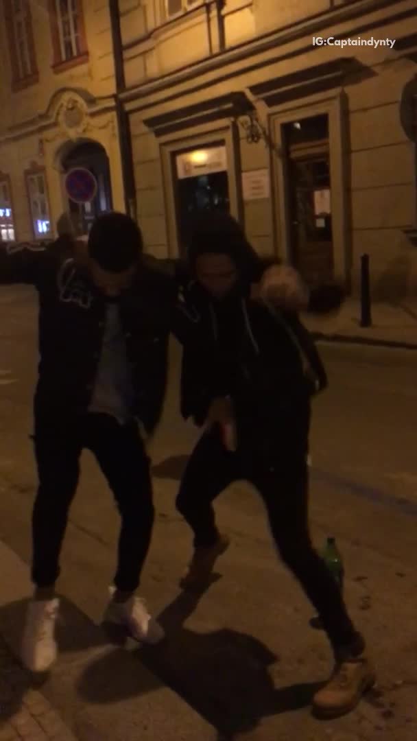 Two guys dance in the middle of the street at night