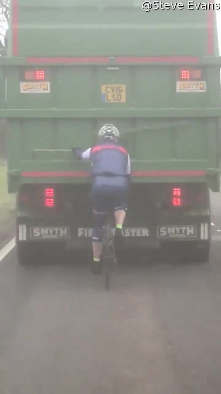 Cyclist Hitching a Ride Holding onto a Truck