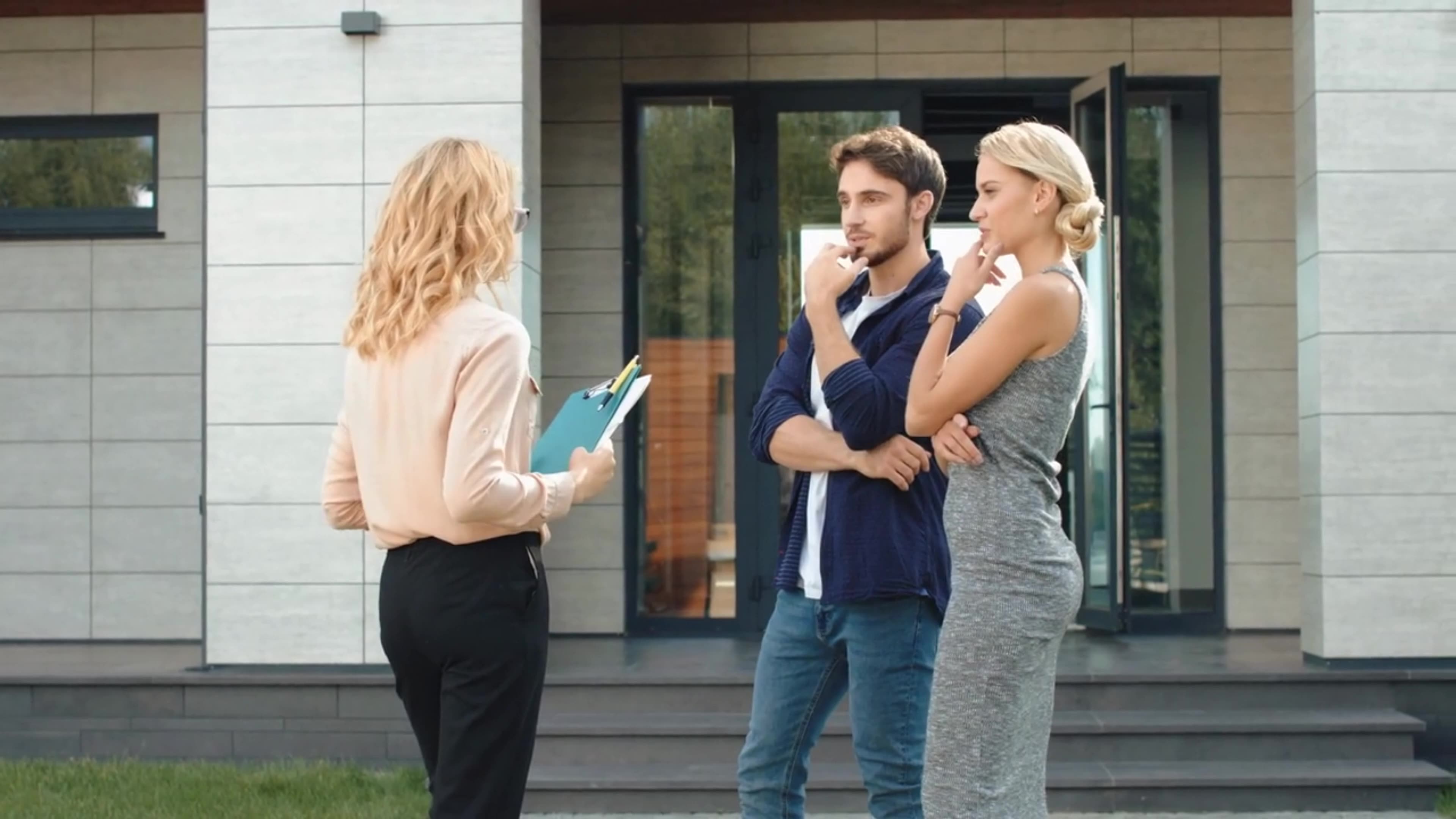 Real estate agent showing a modern house to a young couple.