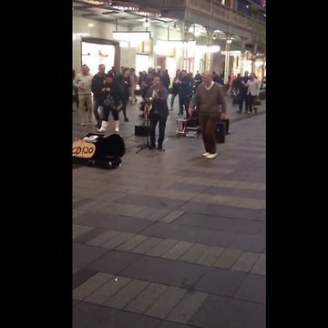 Elderly gentleman dances to street performer