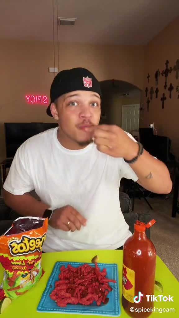 Man eats hot cheetos with hot sauce
