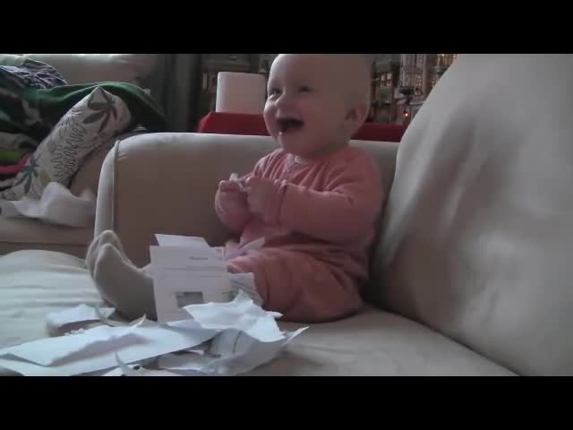 Cute baby laughing at ripping paper